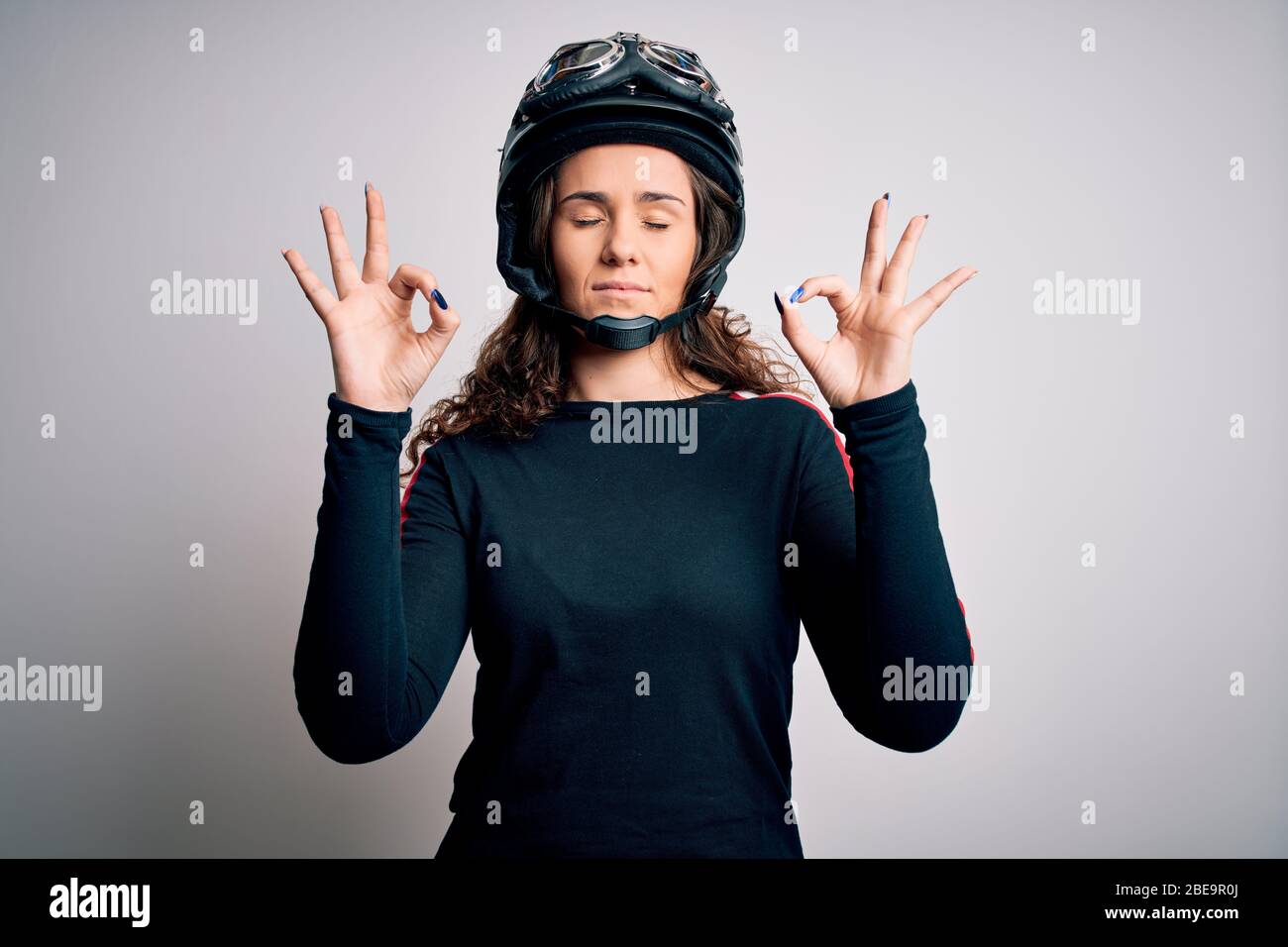 Beautiful motorcyclist woman with curly hair wearing moto helmet over ...