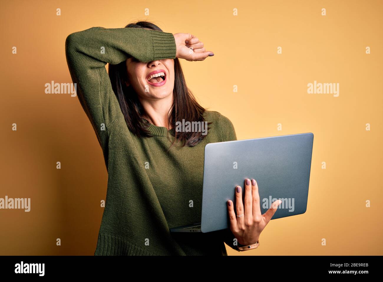Young brunette woman with blue eyes working using computer laptop over ...