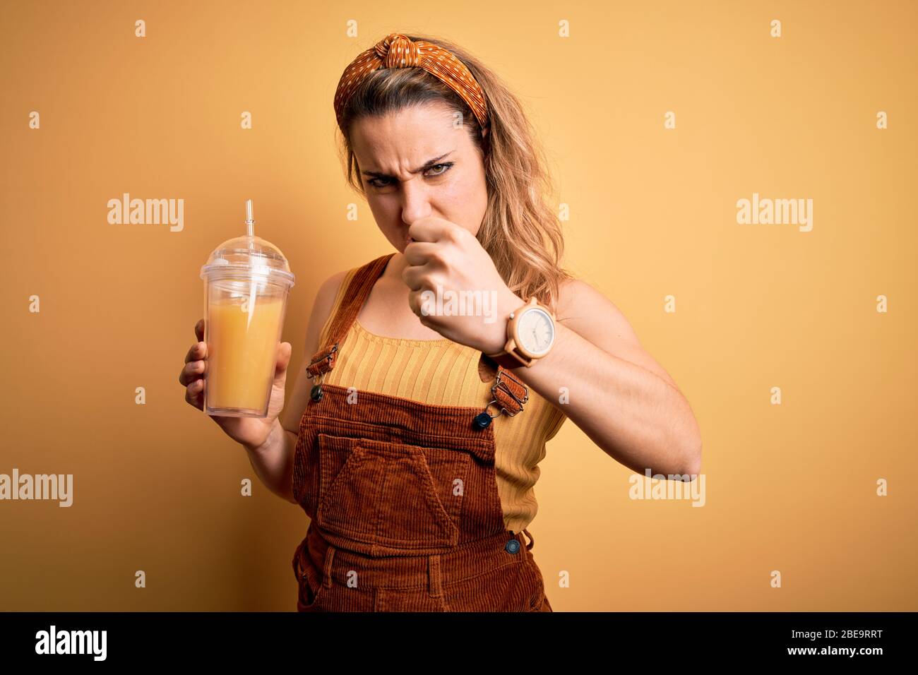 Young beautiful blonde woman drinking healthy glass of orange juice ...