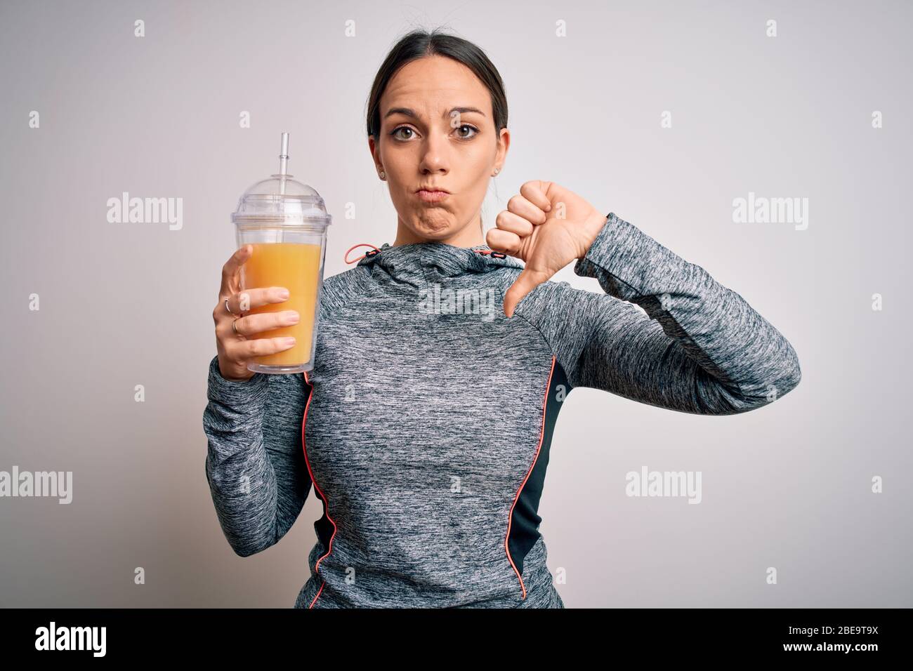 Young fitness woman wearing sport workout clothes drinking fresh orange ...