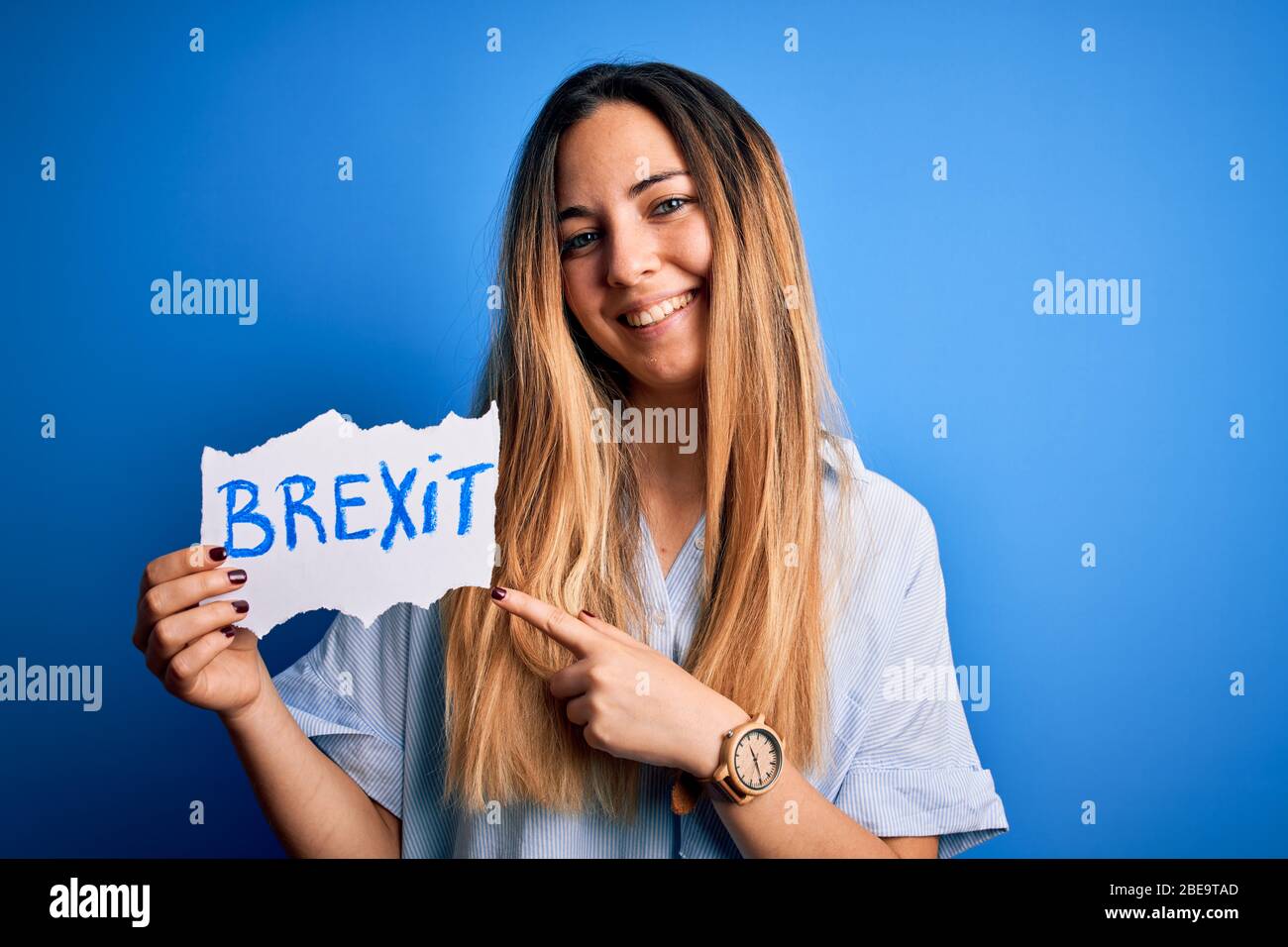 Young beautiful blonde woman with blue eyes holding banner with brexit ...