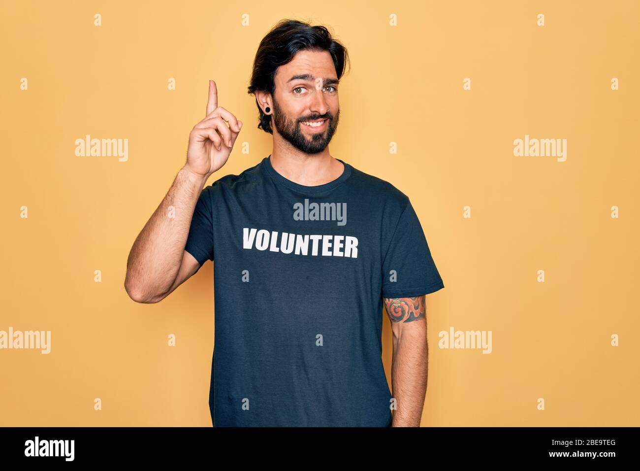 Young handsome hispanic volunteer man wearing volunteering t-shirt as ...