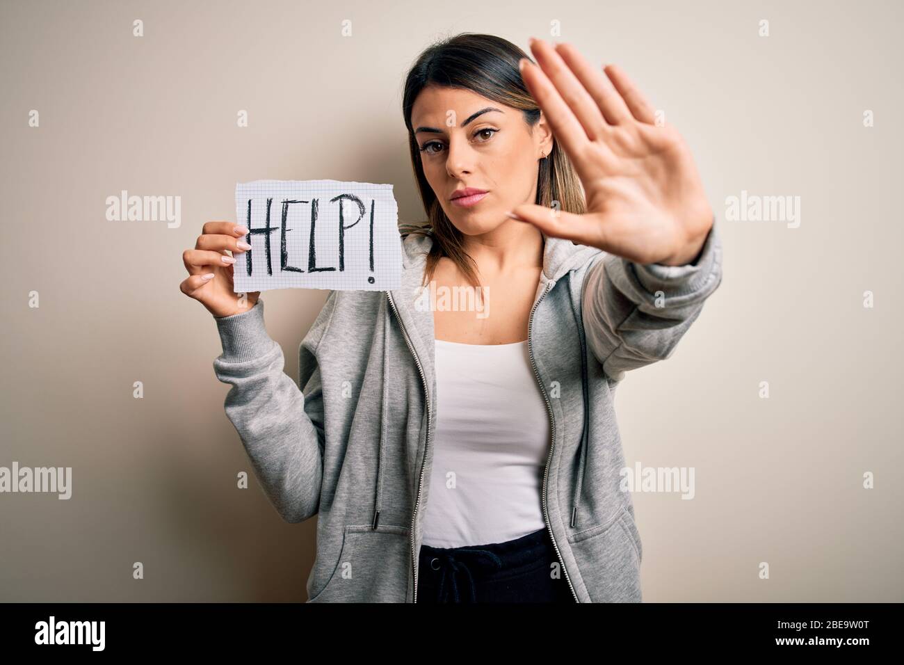 Young beautiful brunette woman holding paper with help message over ...