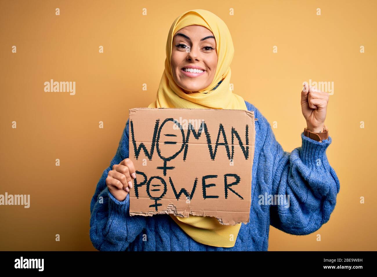 Young beautiful arab woman wearing islamic hijab holding banner with ...
