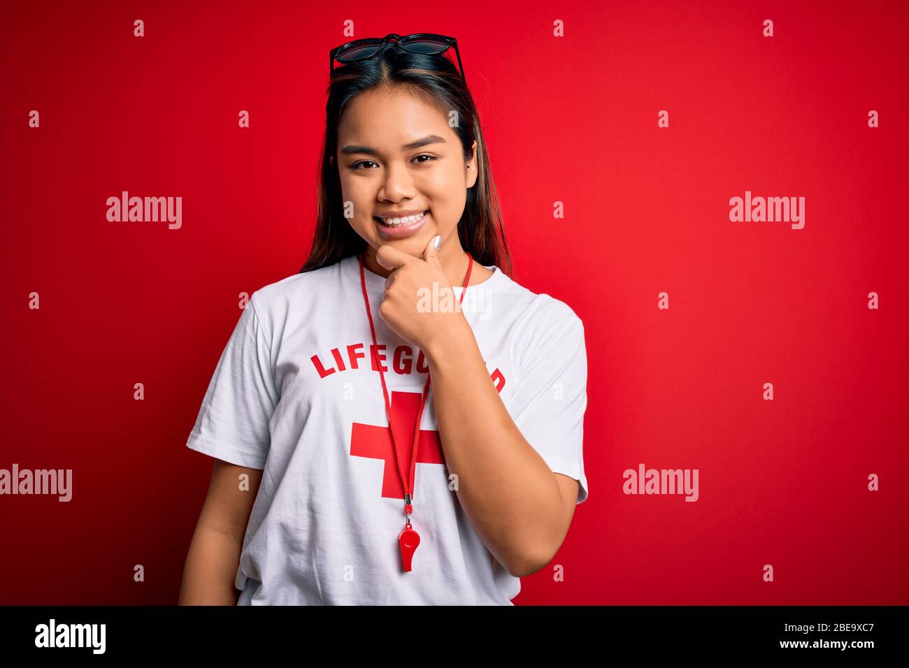 Young asian lifeguard girl wearing t-shirt with red cross using whistle ...