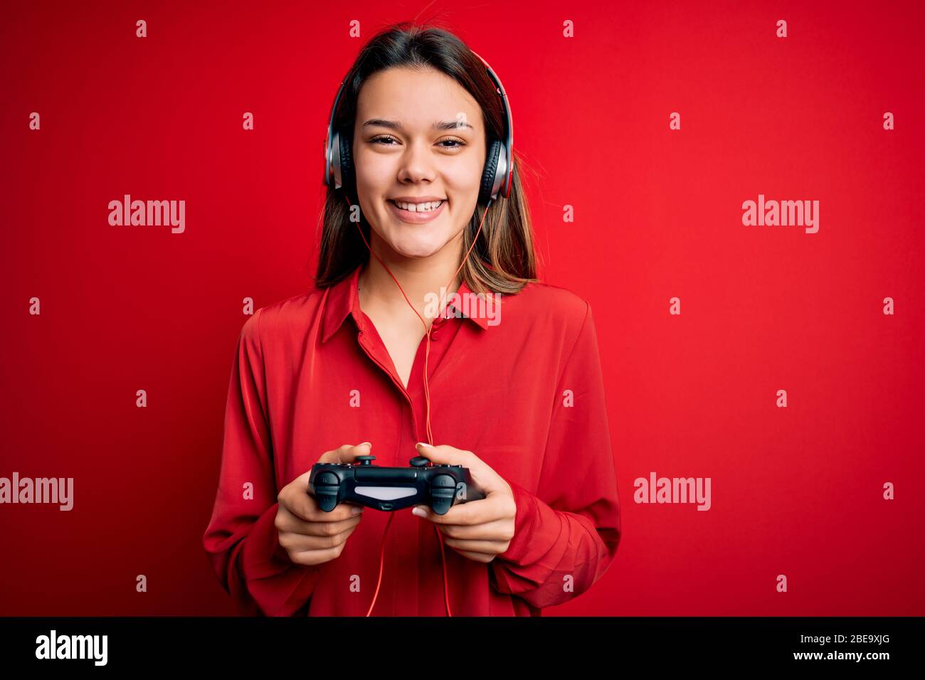 Young beautiful brunette gamer girl playing video game using joystick ...