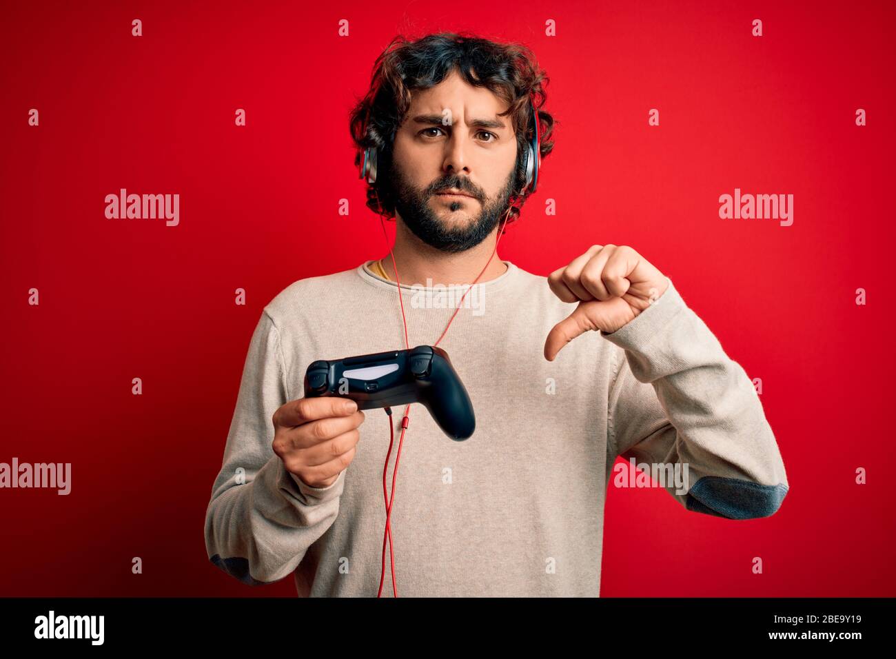 Young gamer man with curly hair and beard playing video game using ...