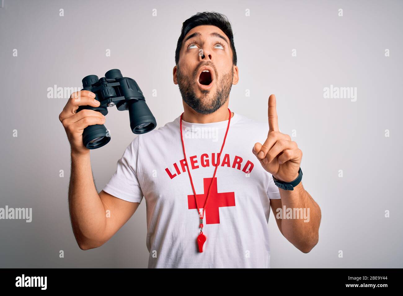 Young lifeguard man with beard wearing t-shirt with red cross and ...