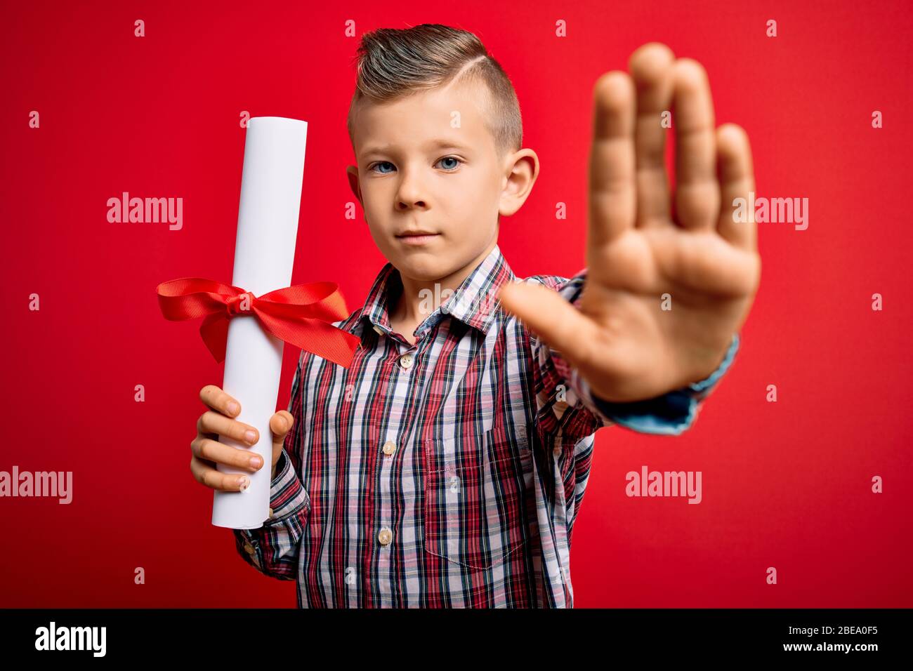 Young little caucasian student kid holding school degree over red ...