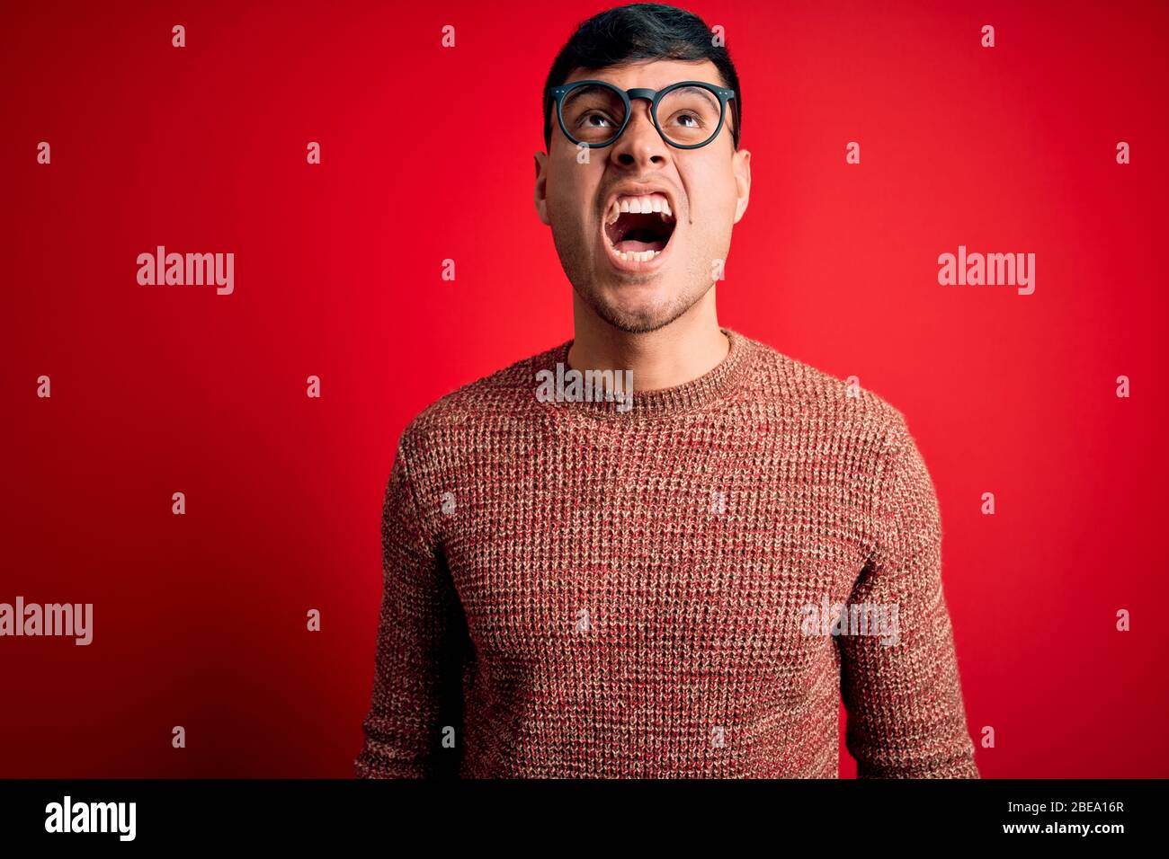 Young handsome hispanic man wearing nerd glasses over red background ...