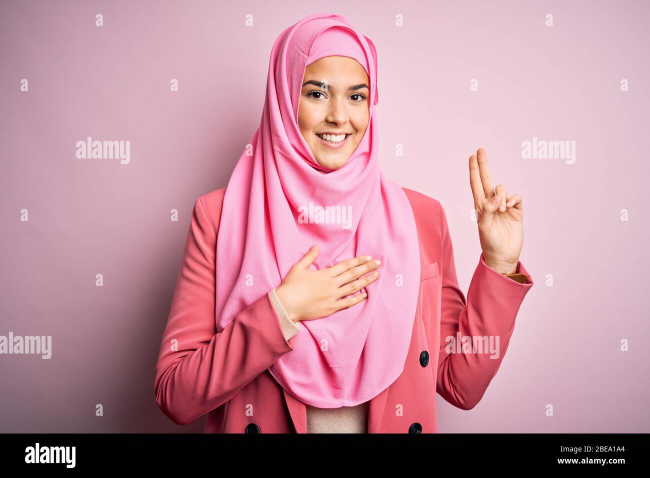 Young beautiful girl wearing muslim hijab standing over isolated pink ...
