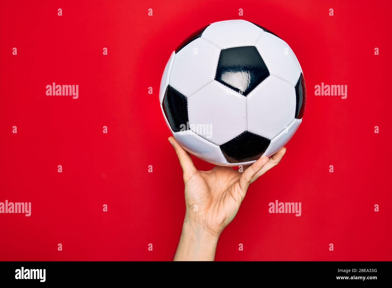 Beautiful hand of man holding football ball over isolated red ...