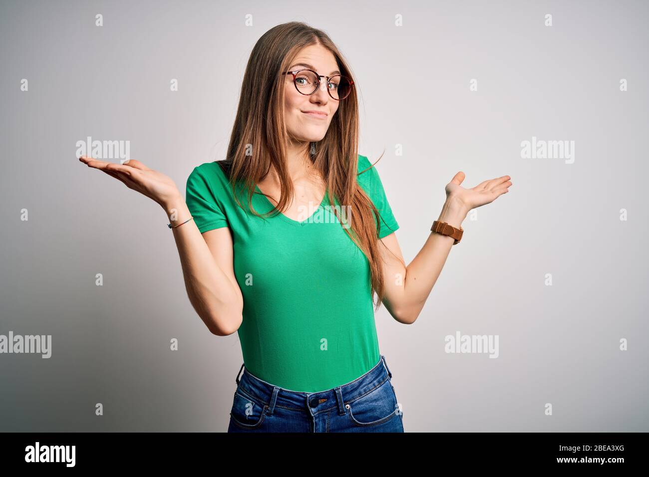 Young beautiful redhead woman wearing casual green t-shirt and glasses ...