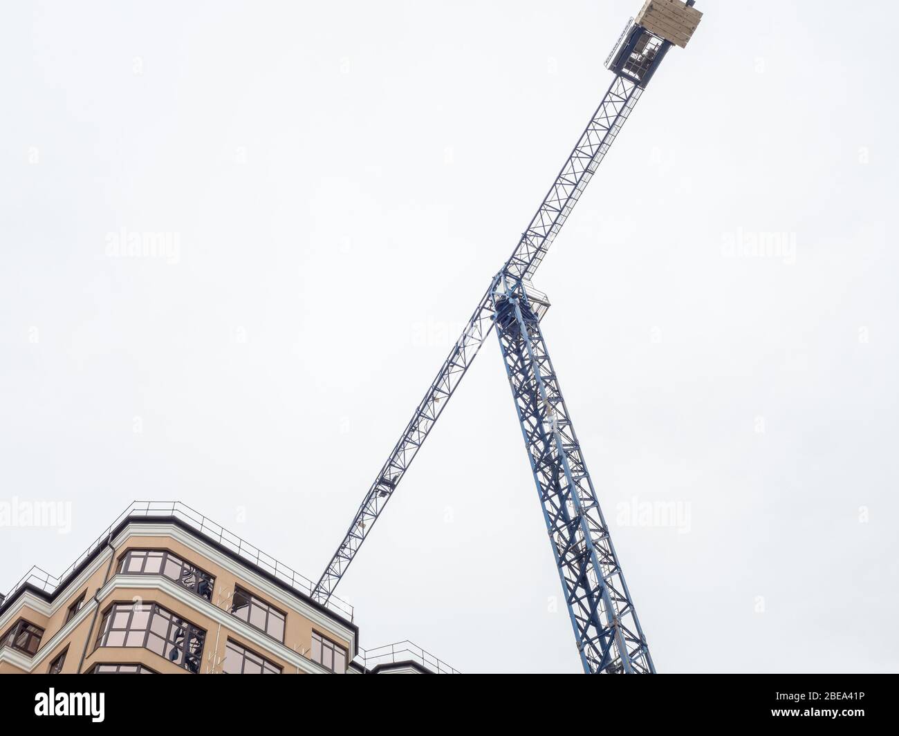 Blue tower crane for building houses on a cloudy sky background near ...