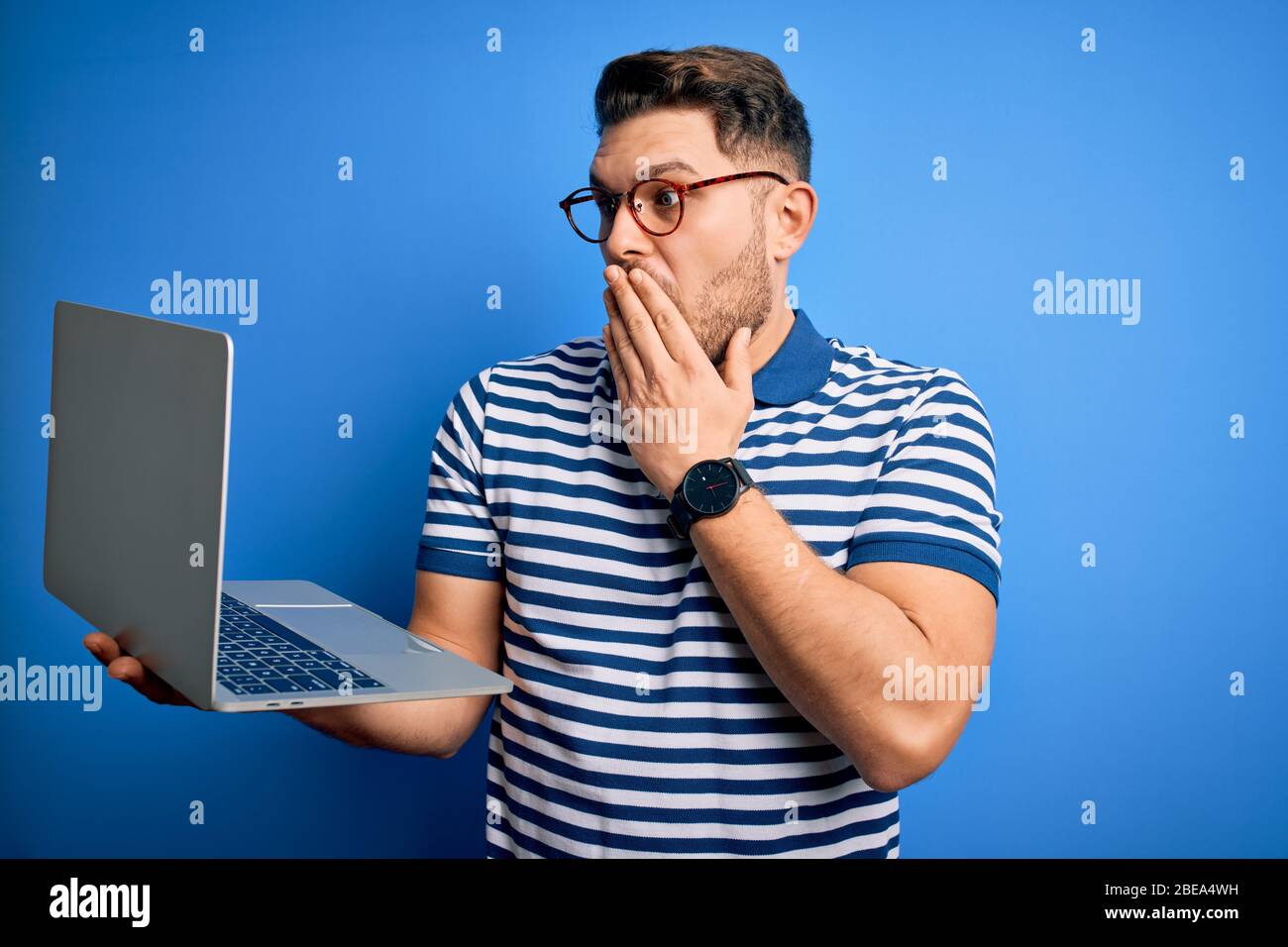 Young business man with blue eyes wearing glasses working using ...