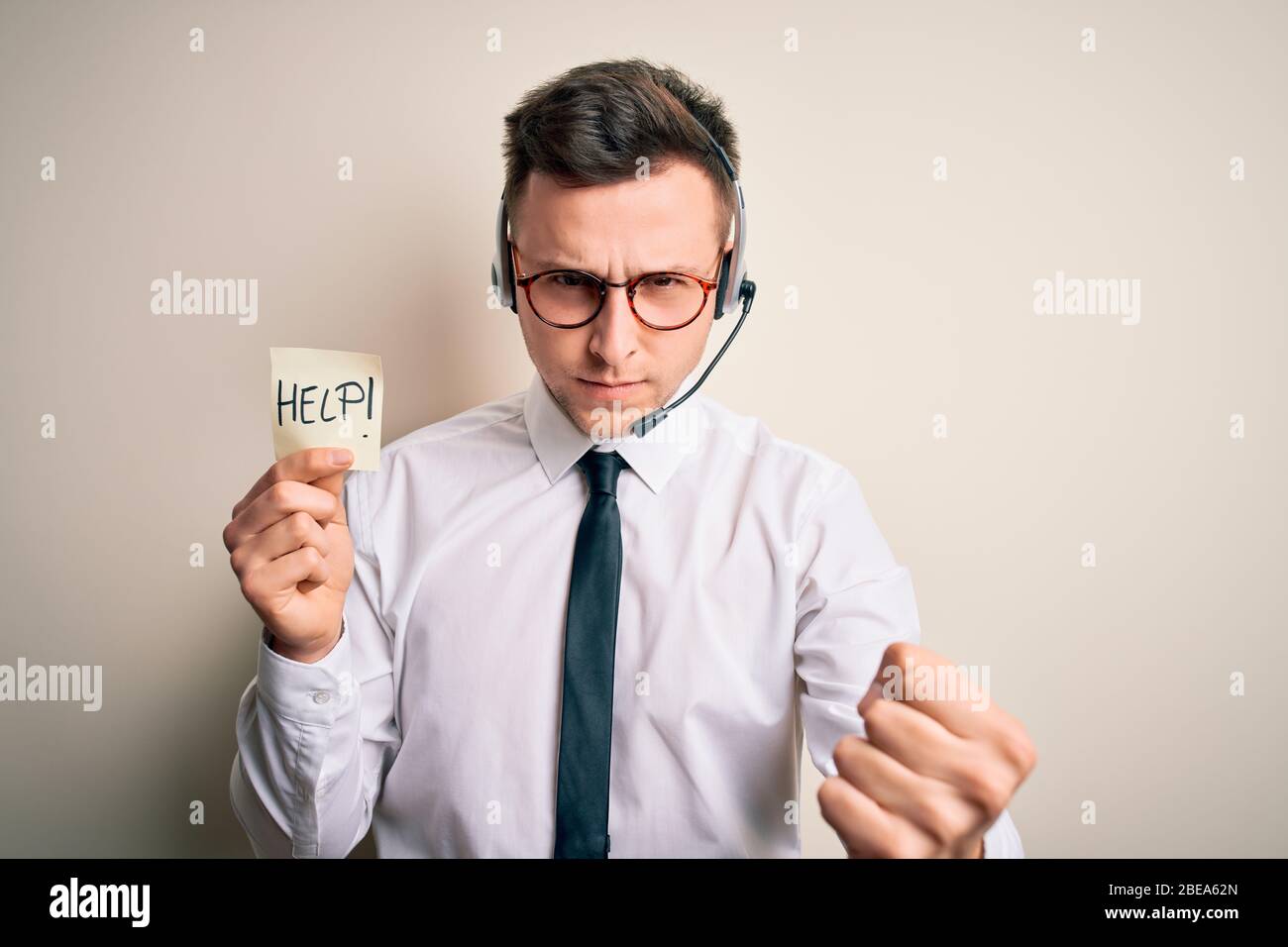 Young call center operator man wearing headset holding paper note with ...
