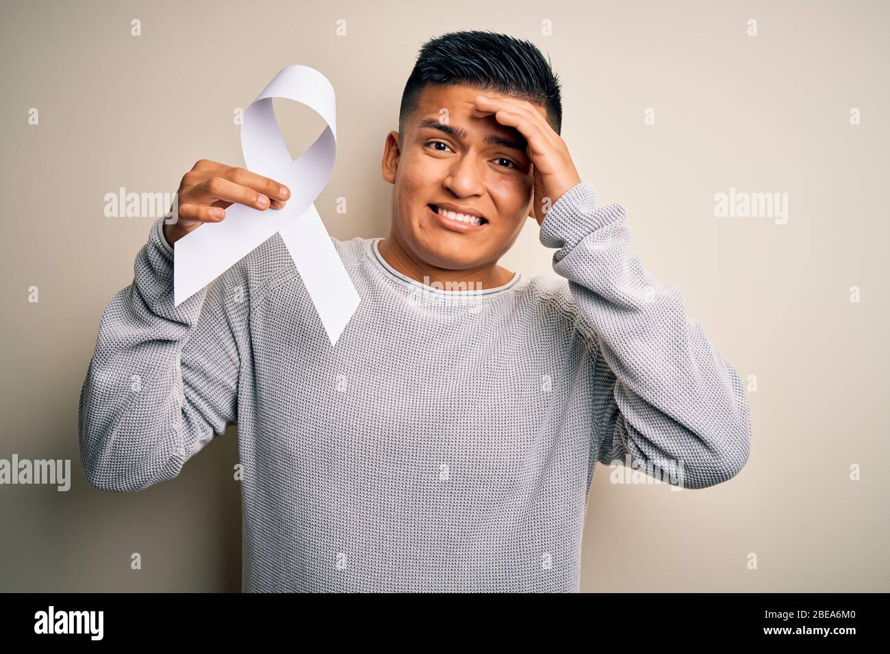Young latin man holding white cancer ribbon supporting stop women ...