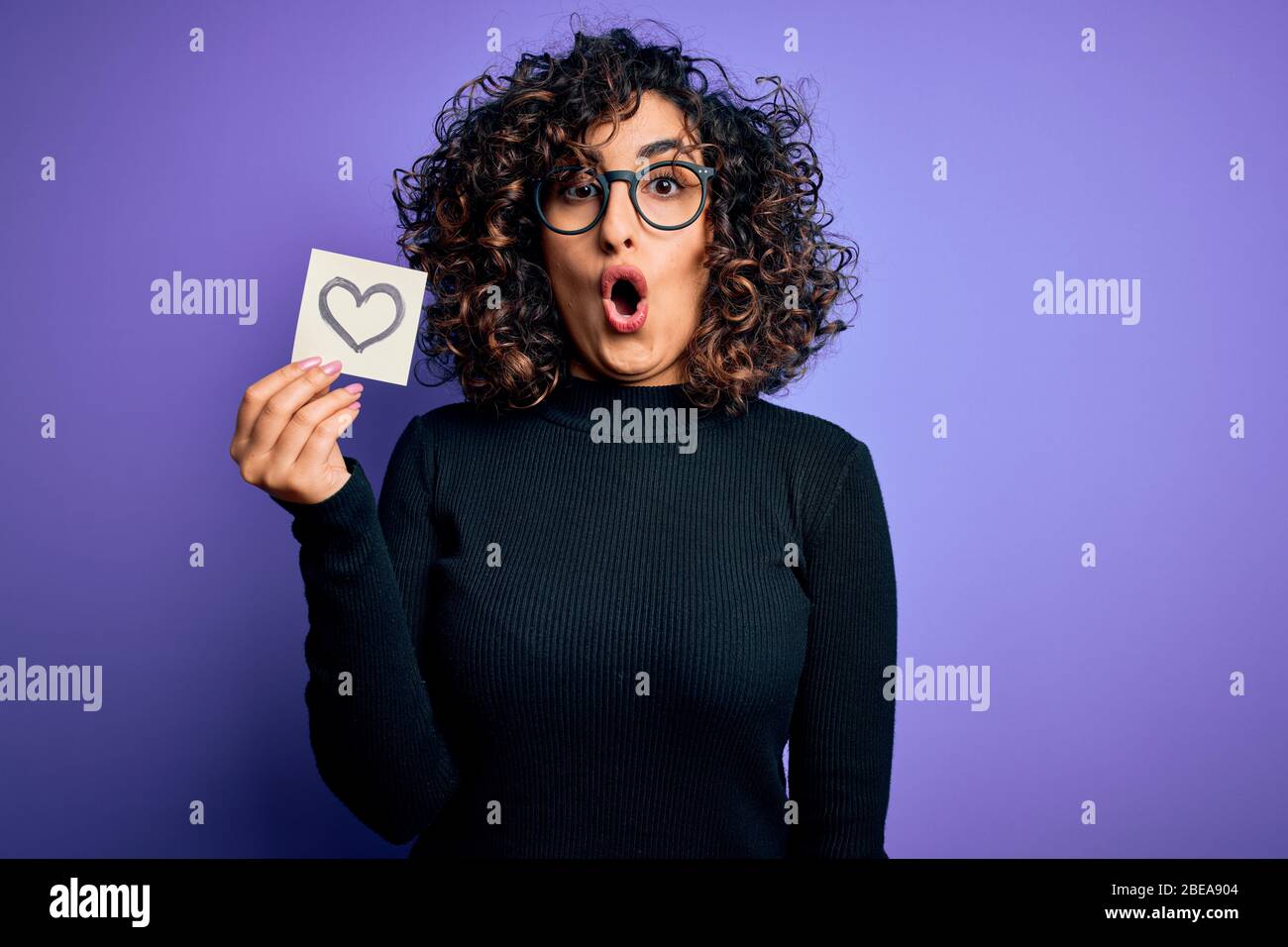 Young beautiful romantic arab woman wearing glasses holding reminder ...