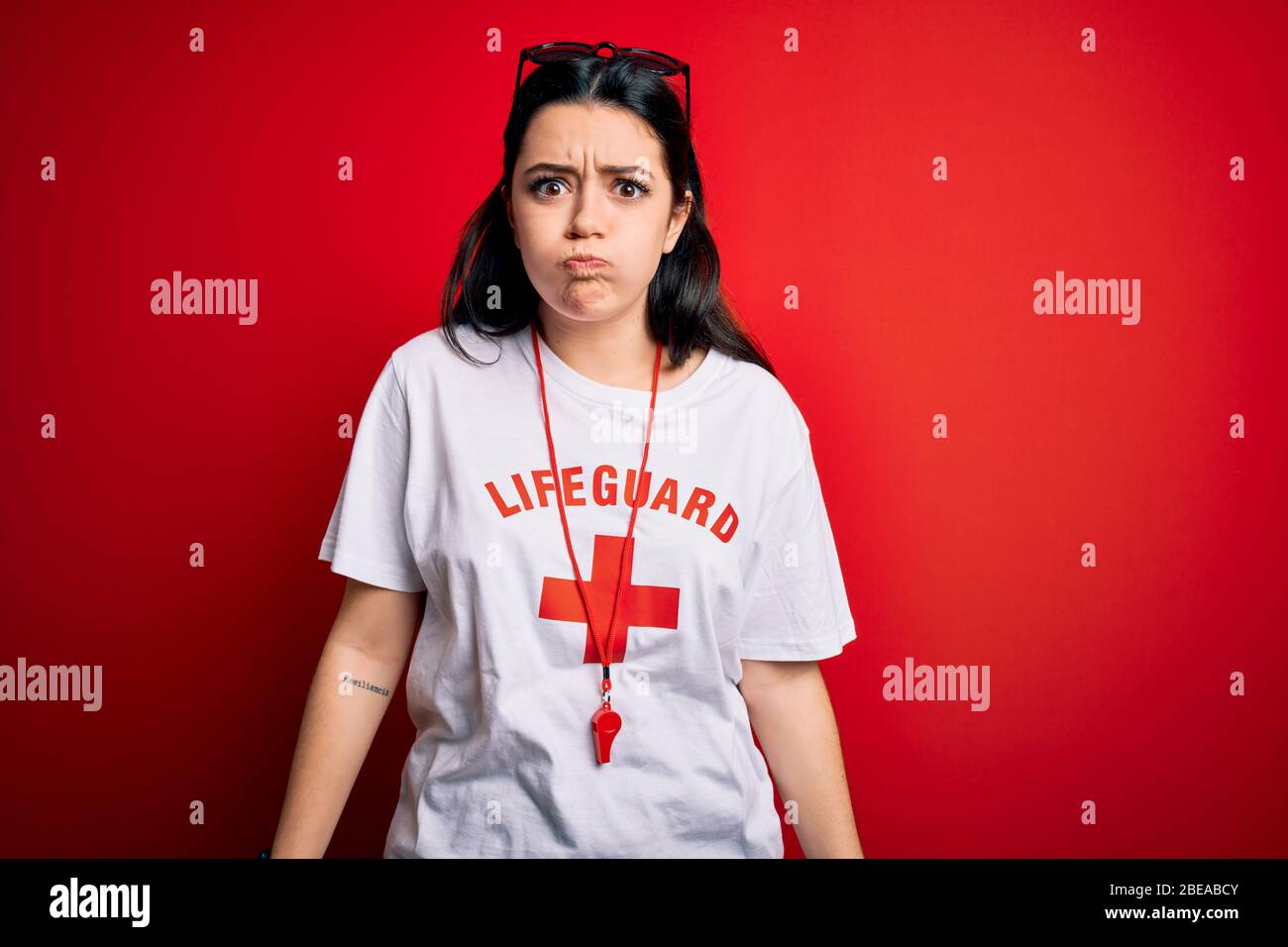 Young lifeguard woman wearing secury guard equipent over red background ...