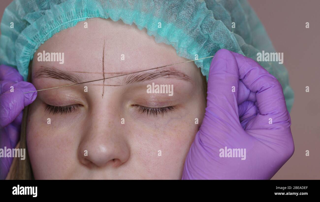 Microbleeding and eyebrow architecture. Beautician builds lines of ...