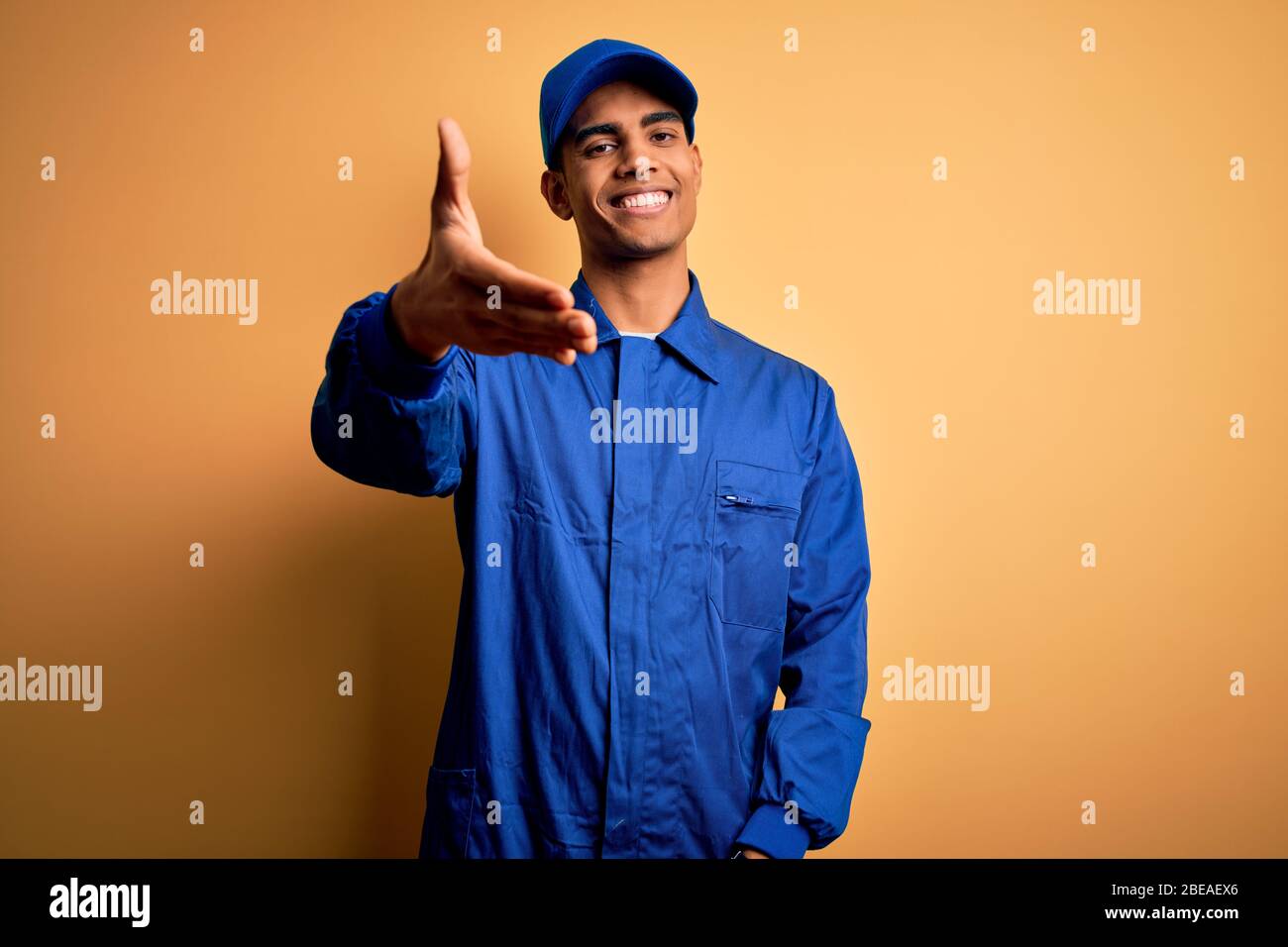 Young african american mechanic man wearing blue uniform and cap over ...