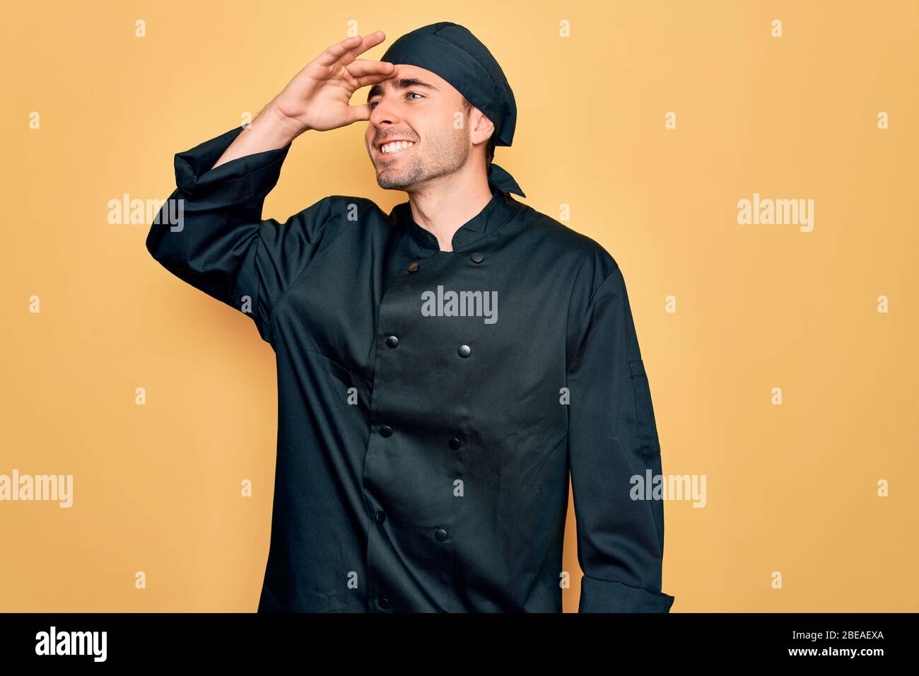 Young handsome cooker man with blue eyes wearing uniform and hat over ...