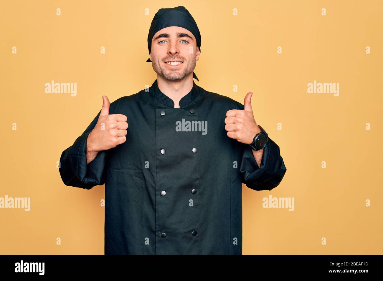 Young handsome cooker man with blue eyes wearing uniform and hat over ...