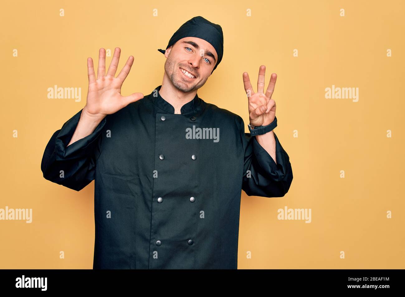 Young handsome cooker man with blue eyes wearing uniform and hat over ...