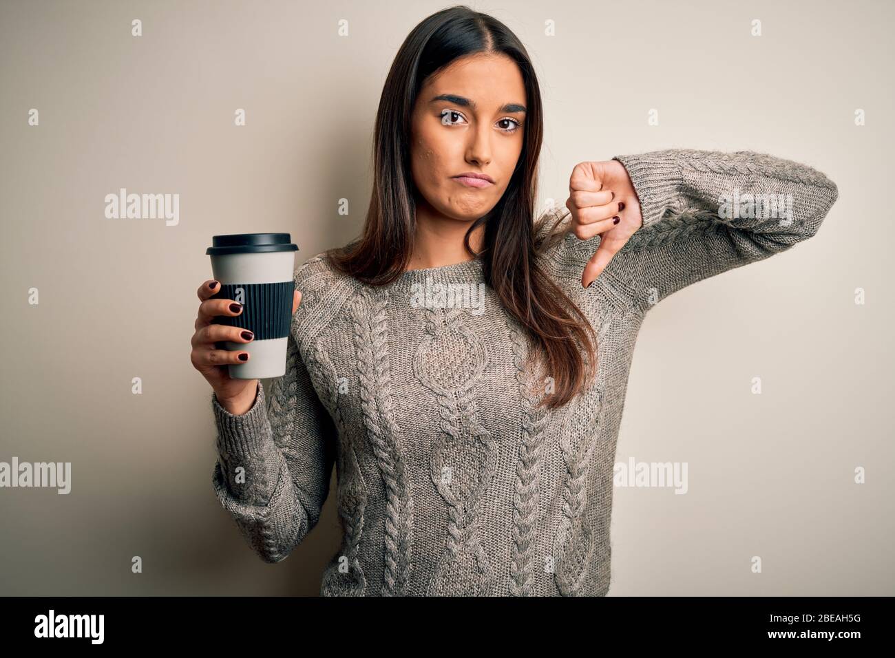Young beautiful brunette woman drinking glass of coffee over isolated ...