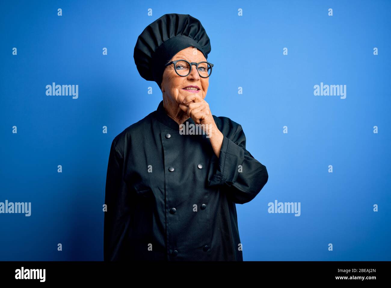 Senior beautiful grey-haired chef woman wearing cooker uniform and hat ...