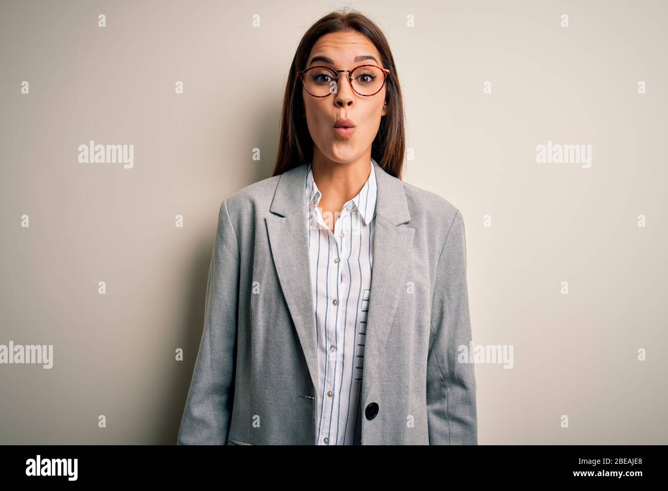 Young beautiful brunette businesswoman wearing jacket and glasses over ...
