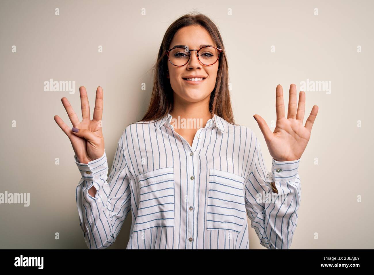 Young beautiful brunette woman wearing casual shirt and glasses over ...