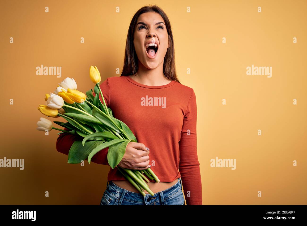Young beautiful brunette woman holding bouquet of tulips flowers over ...