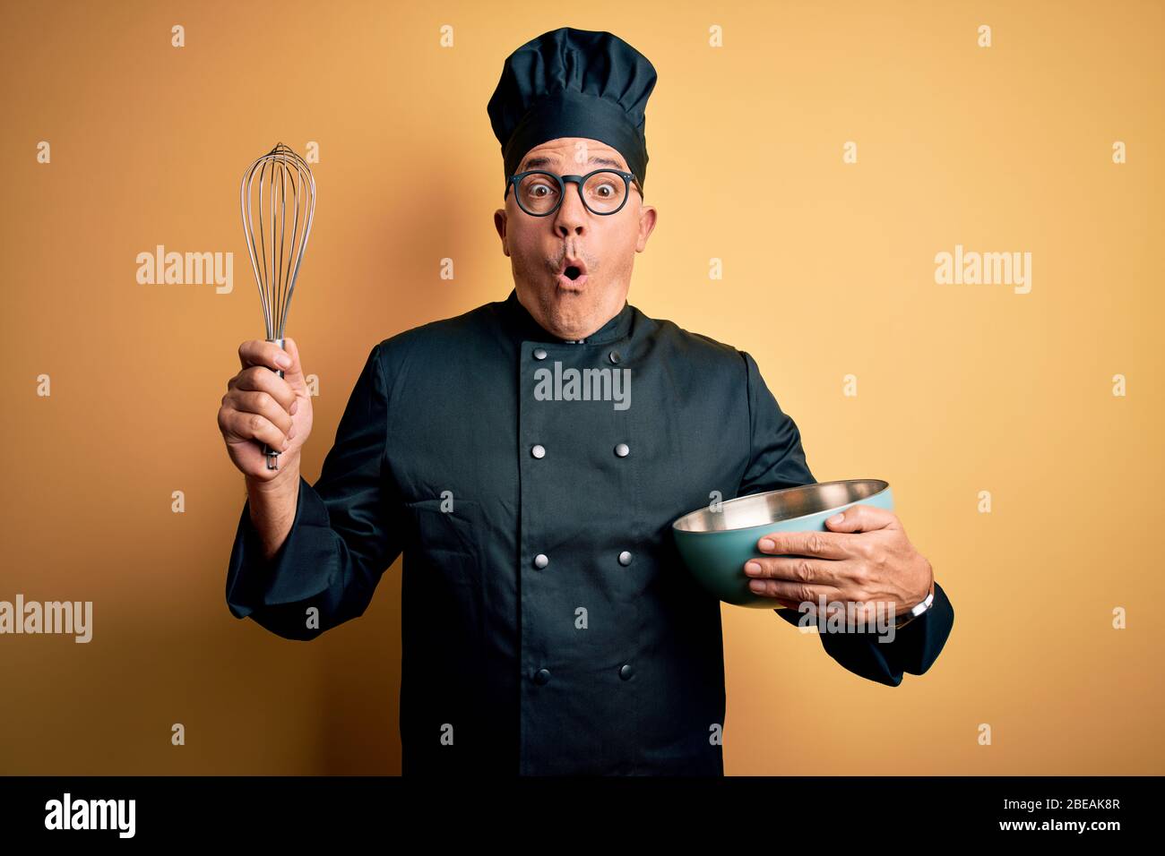 Middle age handsome grey-haired chef man wearing cooker uniform and hat ...