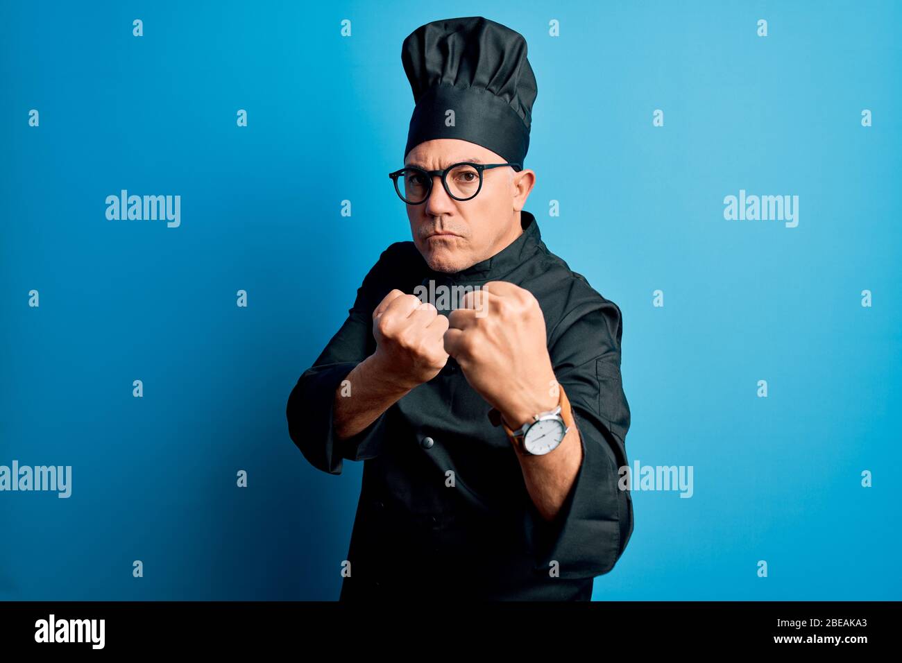 Middle age handsome grey-haired chef man wearing cooker uniform and hat ...