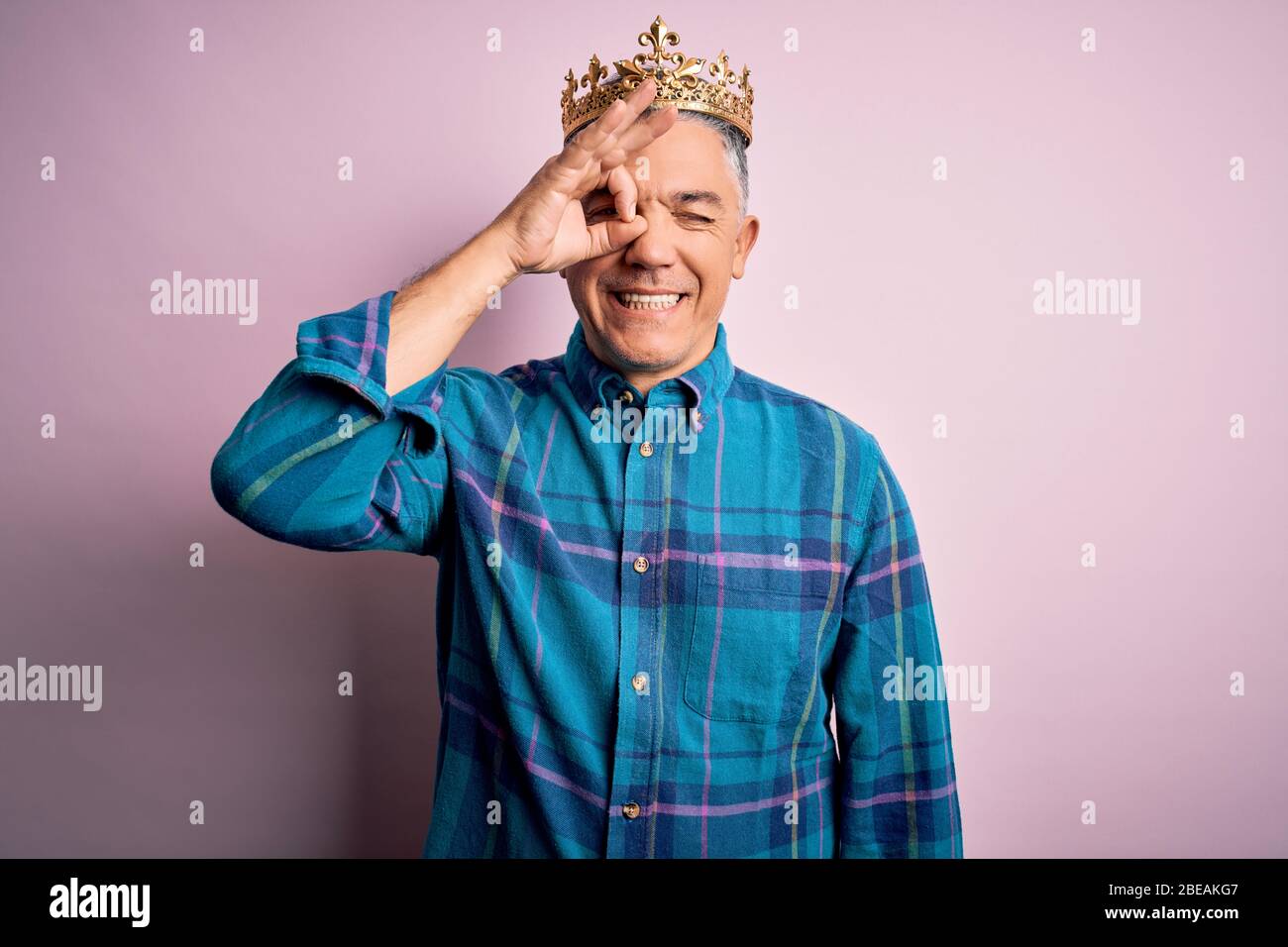 Middle age handsome grey-haired man wearing golden crown of king over ...