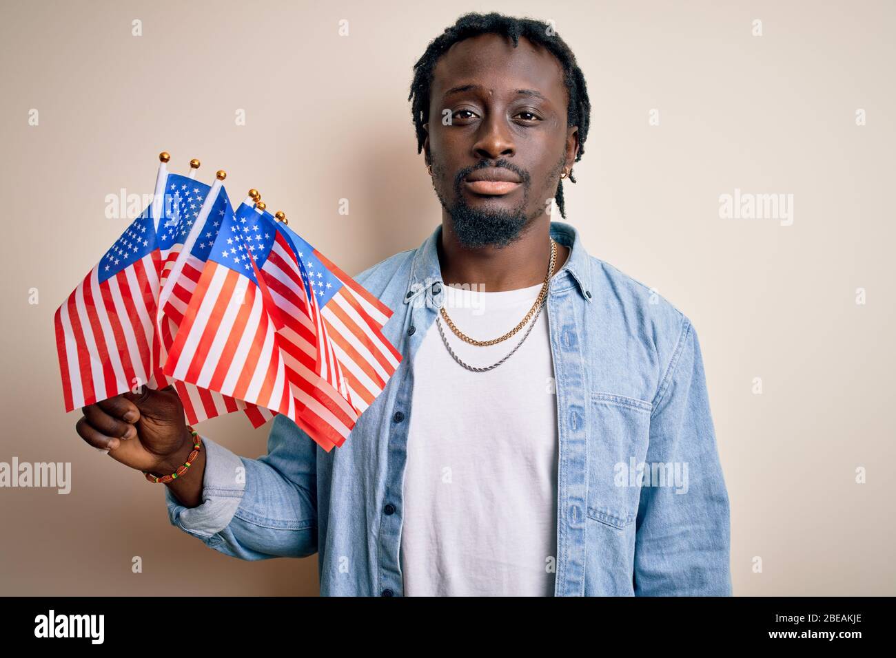 Young african american patriotic man holding united states flags over ...