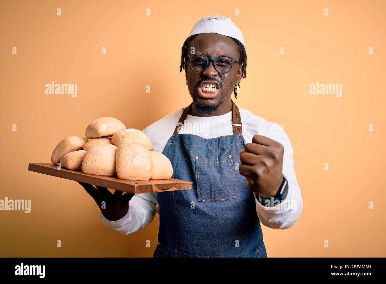 Young african american baker man wearing apron holding tray with ...