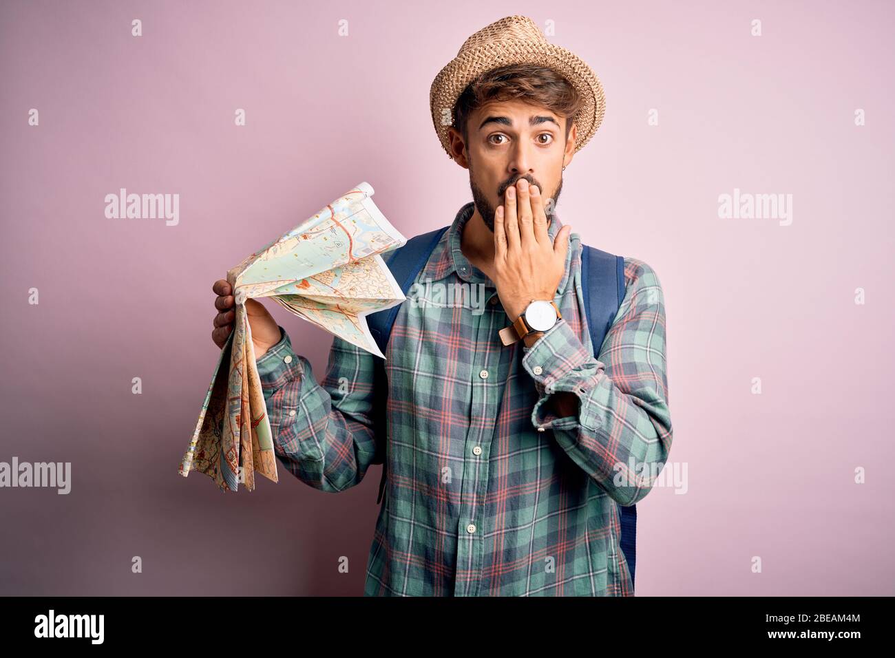 Young tourist man on vacation wearing hat holding city map standing ...