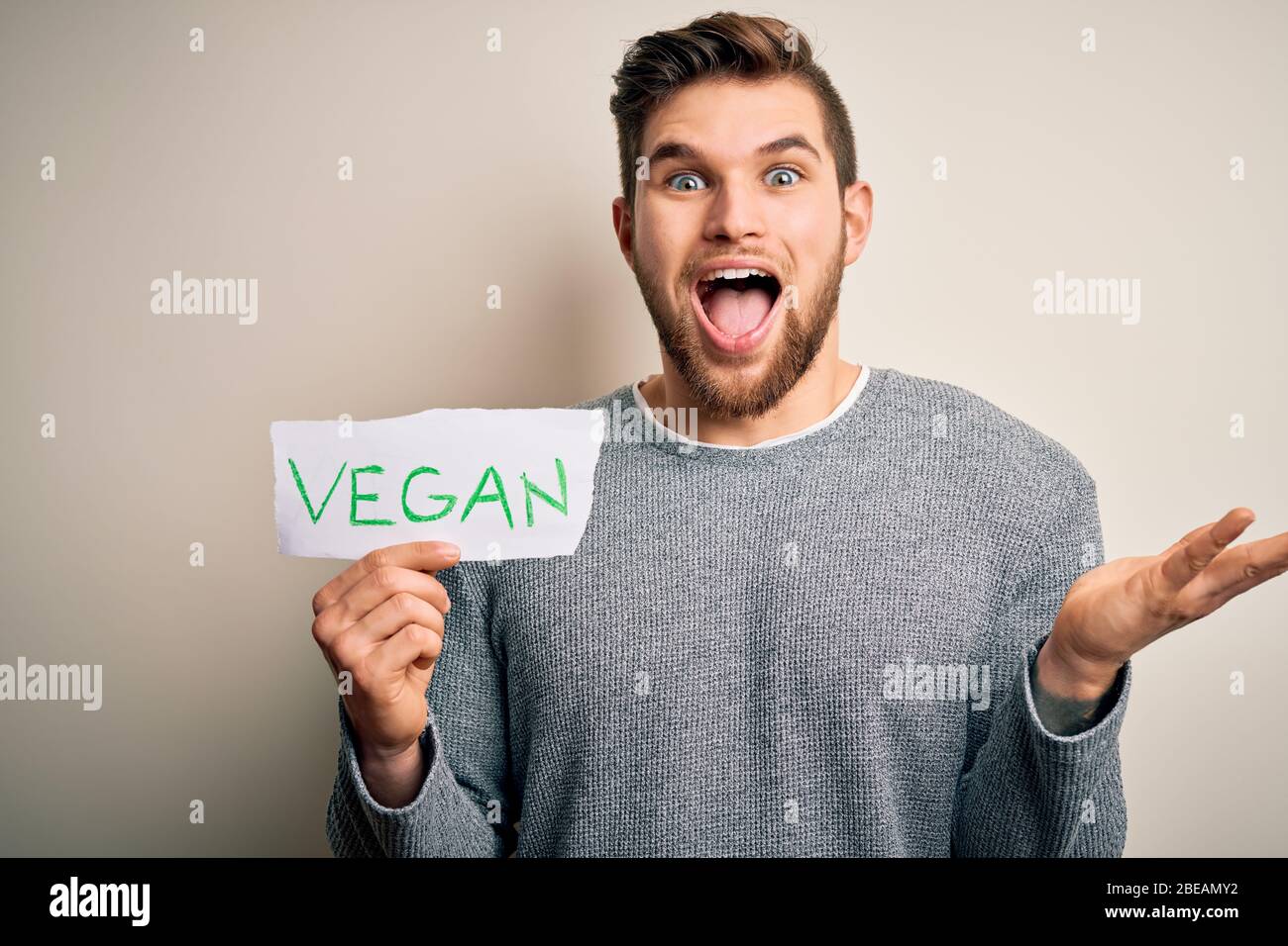 Young blond veggie man with beard and blue eyes holding paper with ...