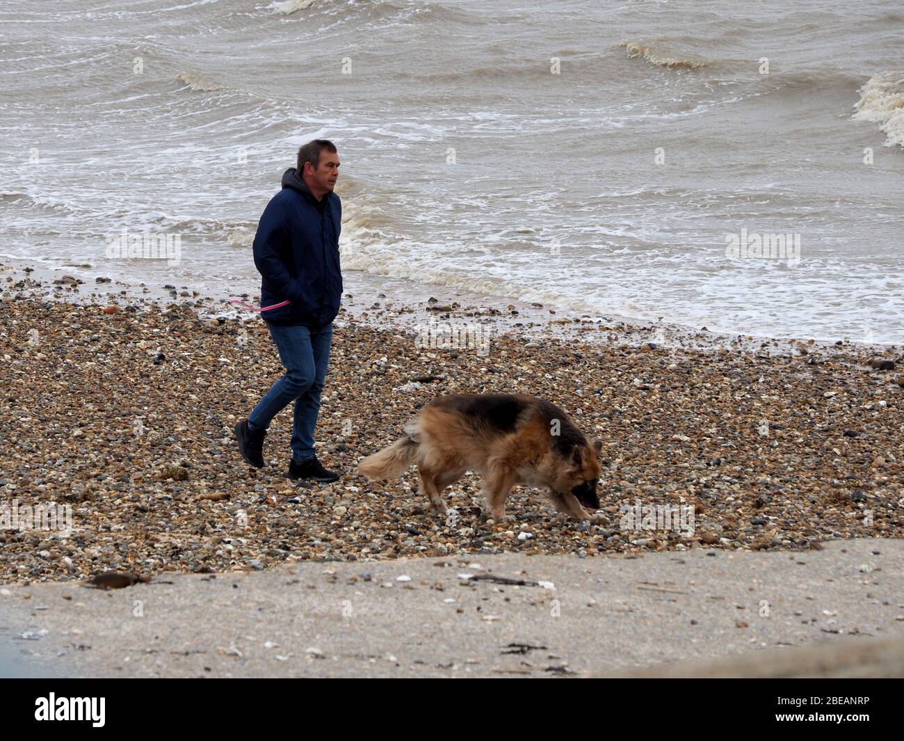 Sheerness, Kent, UK. 13th Apr, 2020. UK Weather: a man walks his dog on ...