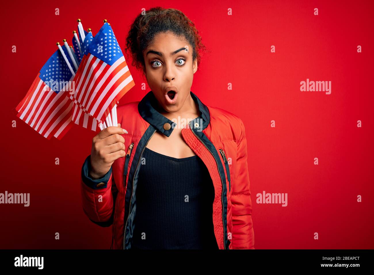 Young african american patriotic girl holding united states flags over ...
