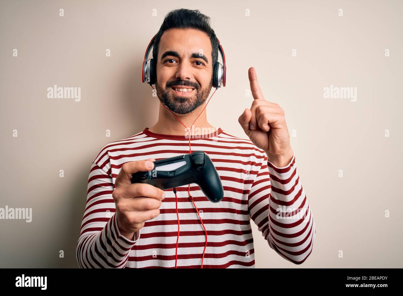 Young handsome gamer man with beard playing video game using joystick ...