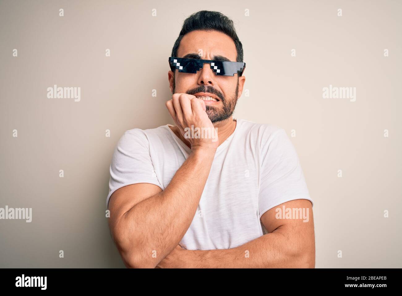 Young handsome man with beard wearing funny thug life sunglasses over ...