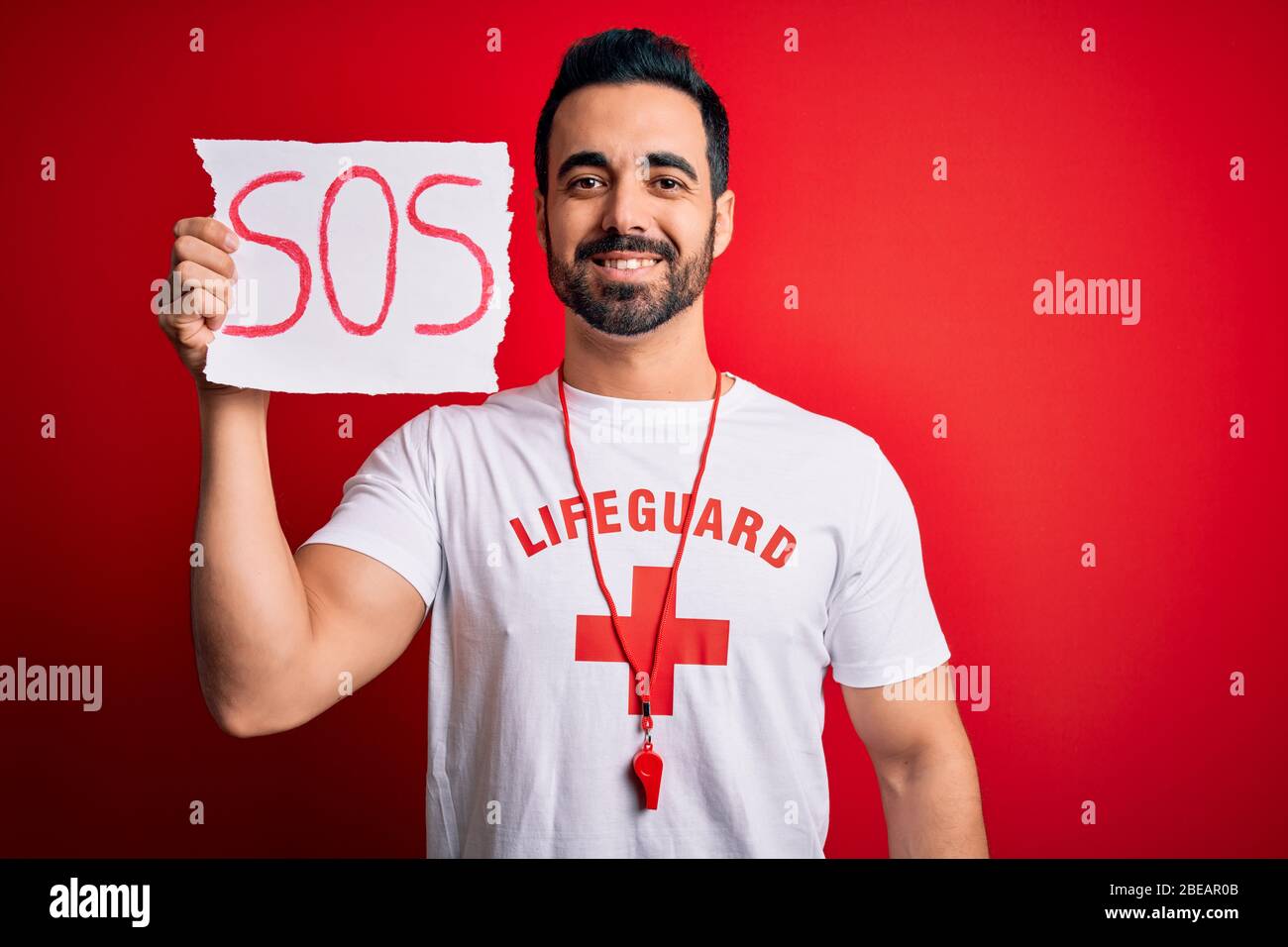 Young handsome lifeguard man with beard wearing whistle holding sos ...