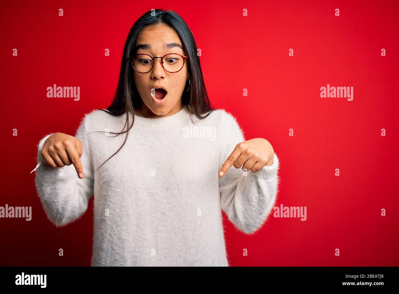 Young Beautiful Asian Woman Wearing Casual Sweater And Glasses Over Red