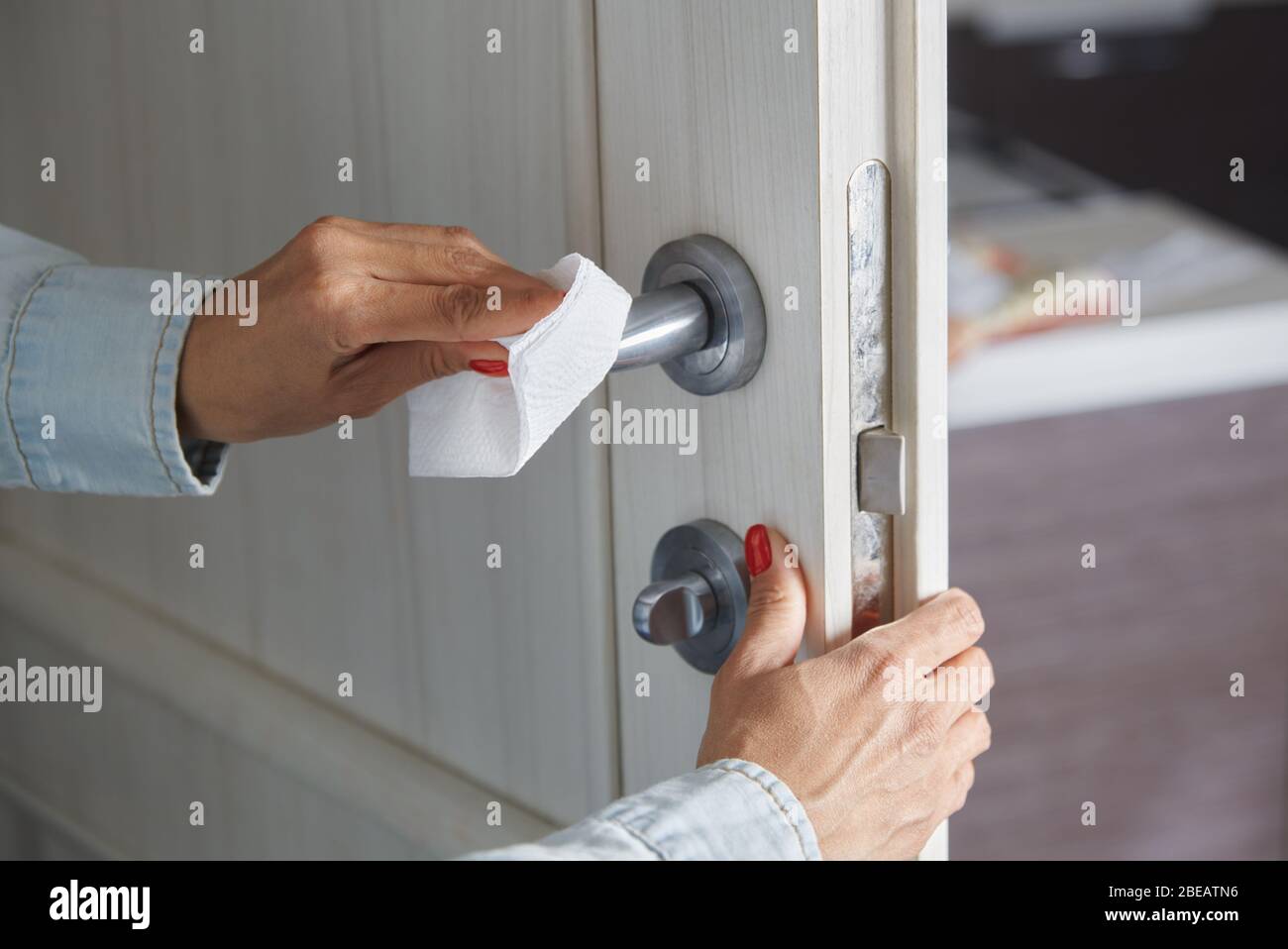 Woman cleaning the door handle with disinfecting wipe Stock Photo - Alamy