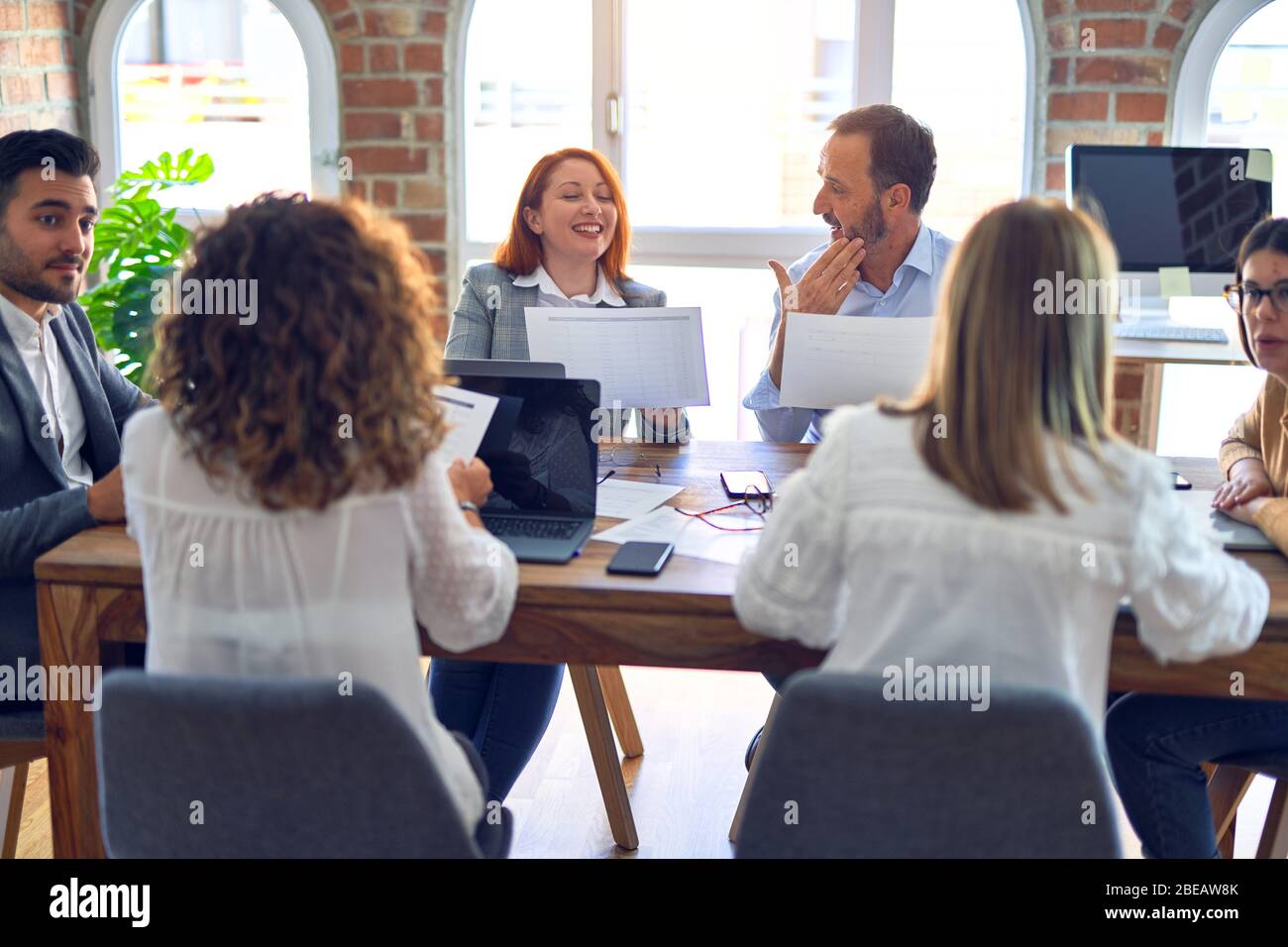Group of business workers working together. Sitting on desk using ...