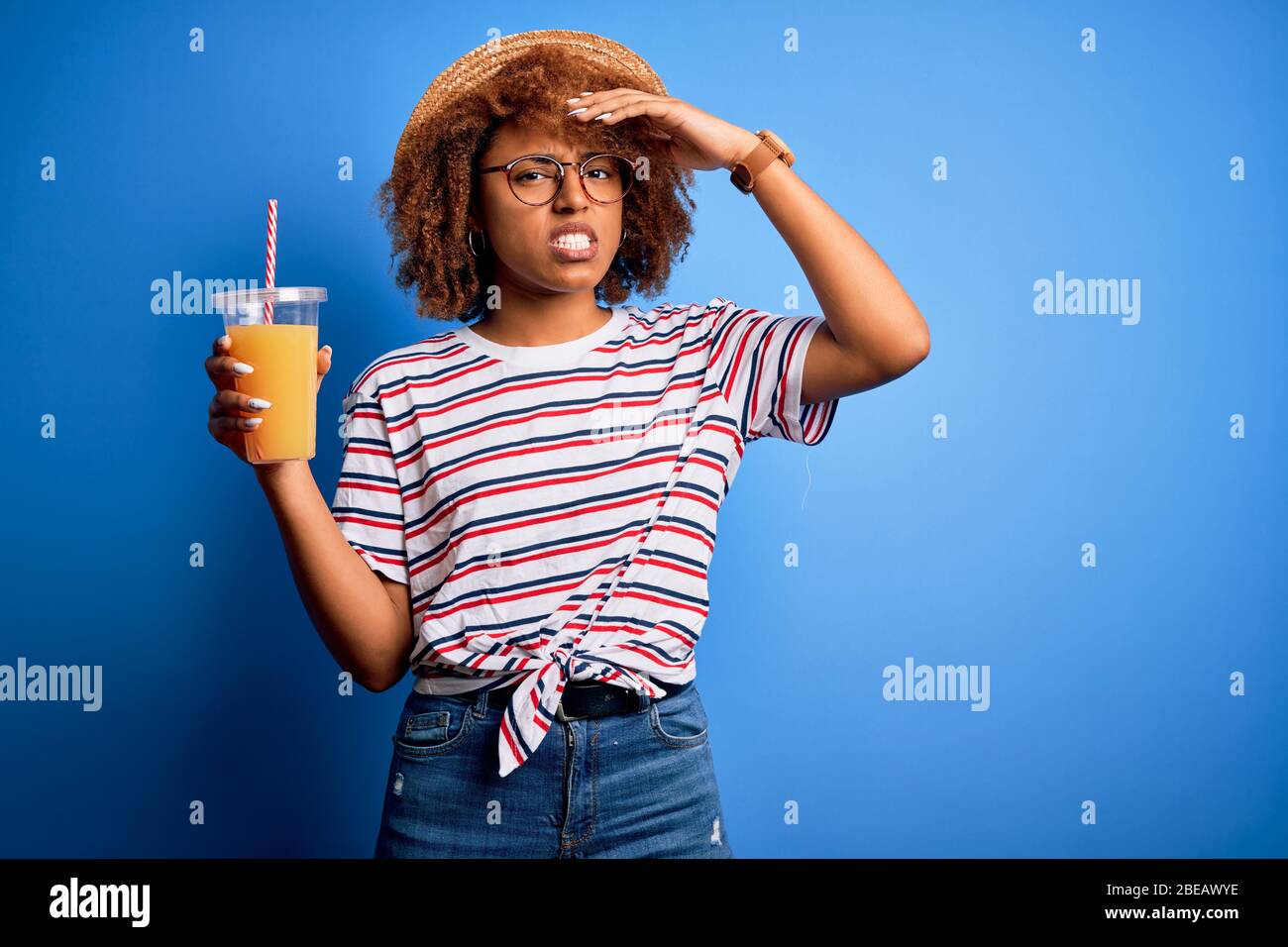 Young African American woman with curly hair on vacation wearing hat ...