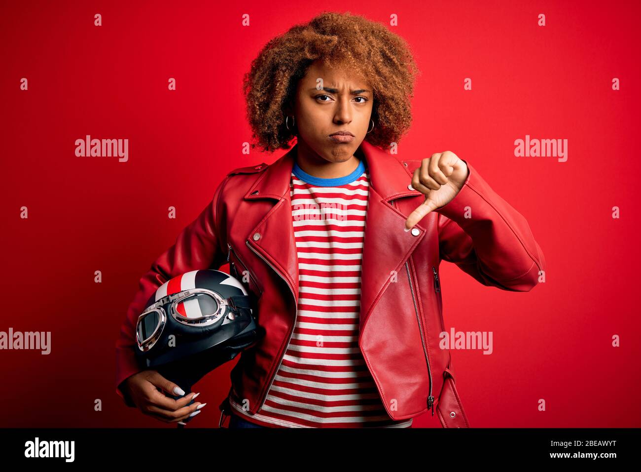 Young African American motocyclist woman holding motorcycle helmet over ...